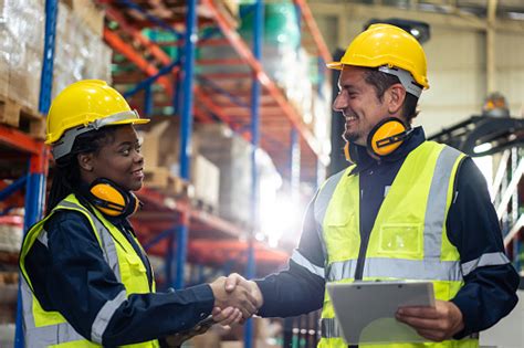 제조 공장에서 함께 일하는 다양한 산업 노동자 팀 매력적인 산업 공장 엔지니어 사람들은 헬멧을 쓰고 행복하게 제조소 창고에서