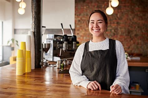 카페의 바 카운터 뒤에 서있는 매력적인 젊은 여성 커피숍 주인의 자른 초상화 바리스타에 대한 스톡 사진 및 기타 이미지