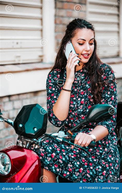 Beautiful Young Woman Talking At Cell Phone While Sitting On Her