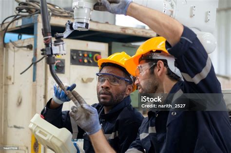 공장에서 자동 기계 로봇으로 함께 일하는 두 명의 엔지니어 남성 기술자 유지 보수 및 개선하면서 원격 산업 및 혁신 개념으로 로봇 및 제어의 Ai를 검사합니다 수리에 대한