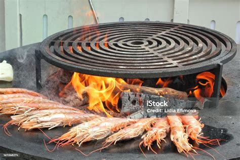 해산물 조각은 원뿔 모양의 그릇 모양으로 화덕 표면에서 조리됩니다 새우와 새우를 곁들인 그릇 모양의 납작한 그릴 야외 바베큐 요리 길거리 음식 개념입니다 뜨거운 구이 토스트