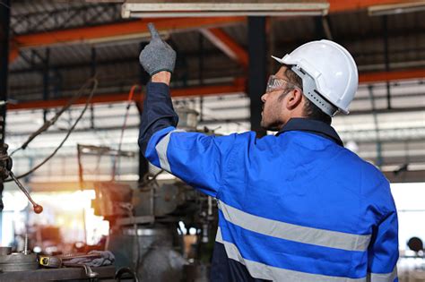 보호복을 입고 서서 워키토키 라디오를 사용하는 후방 기술자 엔지니어가 중공업 제조 공장에서 선반 금속 기계를 제어하거나 유지