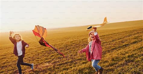 두 명의 어린 소녀 친구가 화창한 낮에 들판에서 연과 장난감 비행기와 함께 즐거운 시간을 보냅니다 사진 Unsplash의 자연 이미지