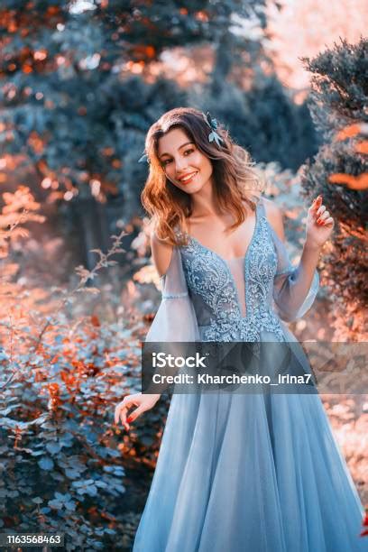 빨간 무성한 장미와 녹색 정원에서 밝은 파란색 드레스에 애정 신부 어두운 머리를 내려다 공주 창조적 인 색상과 매력적인 사진에 대한 예쁜 모델 포즈 여름을 통과의 상징