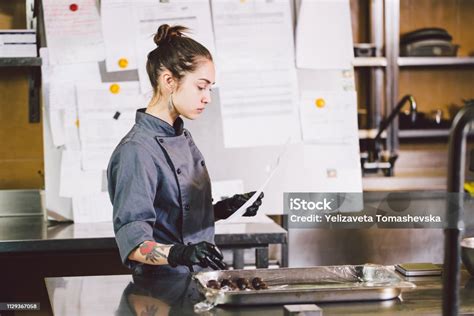지배 직업 그리고 요리 생 과자입니다 젊은 백인 여자 라운드 초콜릿을 준비 하는 레스토랑의 주방에서 제빵의 문신과 검은 장갑과 유니폼에서 수 제 트 러 플 캔디 사탕에 대한