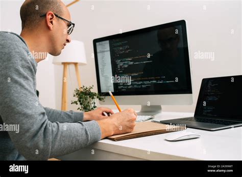 Programmer Working Behind The Desk Analysing Code On The Black Screen