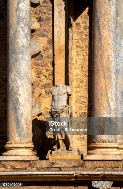 엑스트레마두라의 고전적인 머리 없는 동상과 그리스와 로마 기둥의 유적으로 화강암과 암벽에 그림자를 만드는 새벽 빛의 대비에 의해 조각상에 대한 스톡 사진 및 기타 이미지