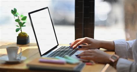 흰색 빈 화면 컴퓨터 노트북으로 작업하는 자신감 넘치는 여성의 자른 이미지는 현대적인 사무실 유리 벽 위에 나무 작업 책상을 배경으로 하고 있습니다 사진