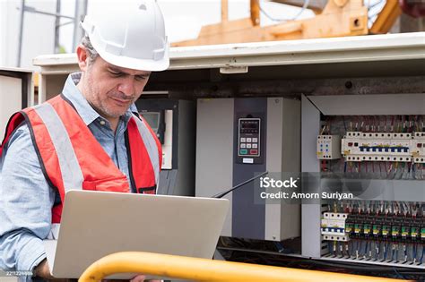 전기 기사 건설 현장 콘솔 캐비닛의 전기 회로 기판 랩톱 컴퓨터를 사용하여 전기 기사 건설 현장에서 전기 시스템 점검 수리 유지 보수 운영 40 44세에 대한 스톡 사진 및