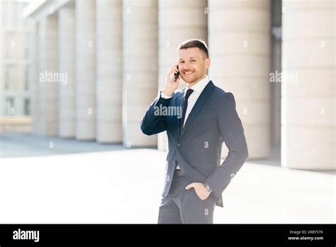 Horizontal Shot Of Satisfied Male With Positive Look Solves Banking Problems While Calls To