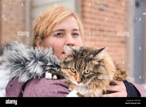 Young Woman Holding Maine Coon Cat With Green Eyes Outside In Snow