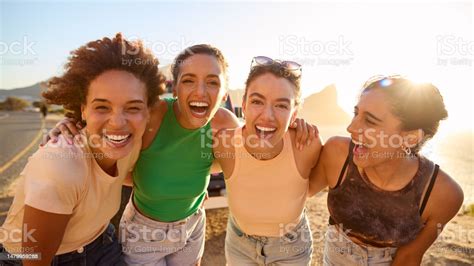 시골을 가로지르는 도로 여행에서 즐거운 시간을 보내는 차 옆에 서 있는 웃는 여자 친구들의 초상화 18 19세에 대한 스톡 사진