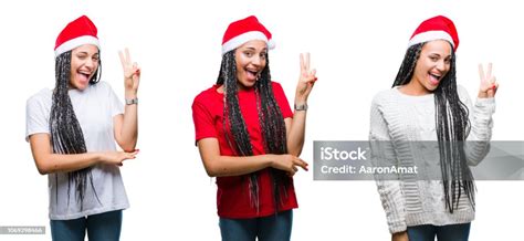 아름 다운 흑인 여 자가 승리 표시를 하 고 카메라에 윙크 하는 행복 한 얼굴로 웃 고 고립 된 배경 위에 크리스마스 모자를