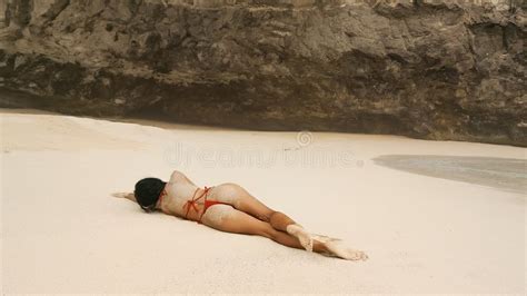 Woman Sunbathing On Secluded Sandy Beach Under Rocky Cliff Cove Stock