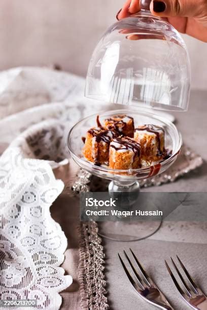 알 샤리야 세몰리나 케이크 디저트 유리 돔에서 한입 크기의 조각으로 제공 우아하고 달콤한 간식의 측면 모습 Eid Ul Fitr