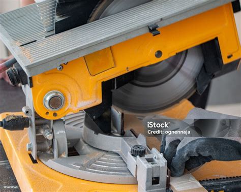 건설 노동자톱과 전기 마이터의 절단 부품의 남성 손은 나무 보드에서 보았다 블레이드 회전과 먼지가 많은 구름 전기 마이터 톱으로 목재 보드 절단 공정 각도절단기에 대한 스톡