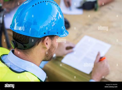 Rear View Of Architect Reading Document At Construction Site Stock Photo Alamy