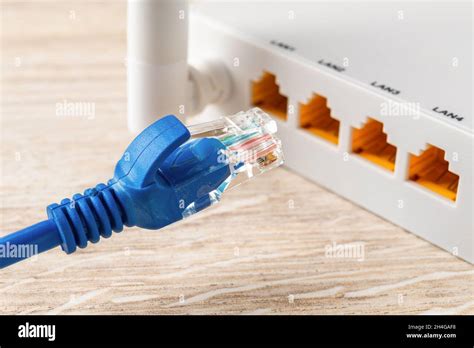 Blue Network Cable Plug Almost Inserted Into The Yellow Socket Of White