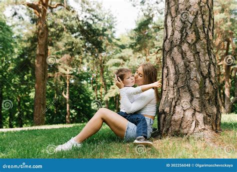 Young Caucasian Mother Kisses Her Three Year Old Son On The Cheek While