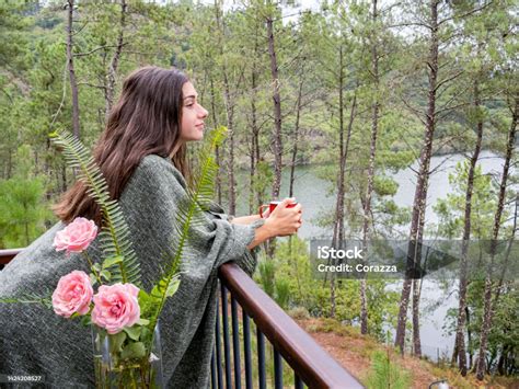 아름다운 백인 여성이 뜨거운 커피를 들고 마시고 발코니에 서서 호수와 녹색 자연을 바라 보는 초상화 이미지 마시기에 대한 스톡 사진 및 기타 이미지 Istock
