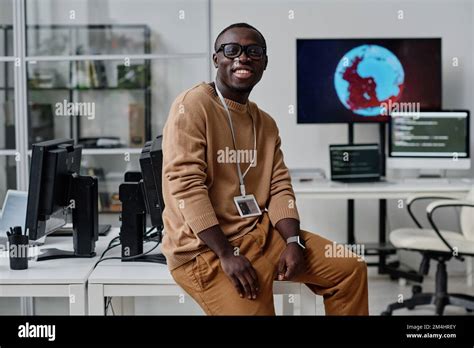 Portrait Of Young African American Developer Smiling At Camera Sitting On His Workplace In It