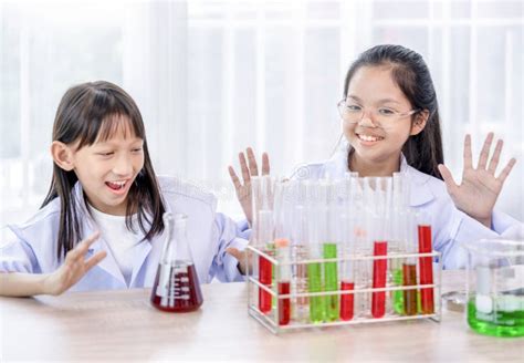 Portrait Cute School Girls In Lab Coat Having Fun When Learning Science In The Classroom Stock