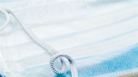 3ply 일회용 수술 용 얼굴 마스크 는 파란색 배경에 입과 코를 덮고 고무 패드와 클로즈업 박테리아 의료 및 의학으로부터