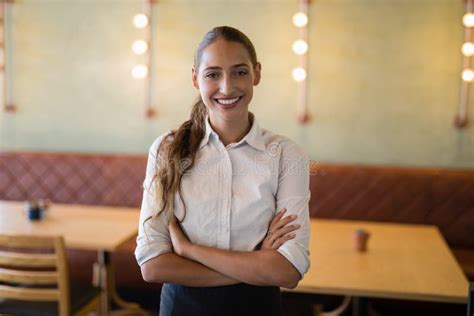 El Camarero De Sexo Femenino Que Se Colocaba Con Los Brazos Cruz En Barra Foto De Archivo