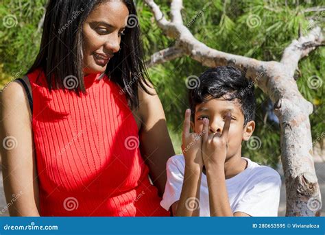 Mother And Son Making Faces While Posing Together Sitting On Grass In The Park Stock Image