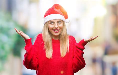 이상의 크리스마스 모자를 입고 젊은 아름 다운 금발의 여 자가 제기 하는 손과 팔으로 배경 우 둔 하 고 혼란 스 러 워 식 고립 의심 개념입니다 감정에 대한 스톡 사진 및