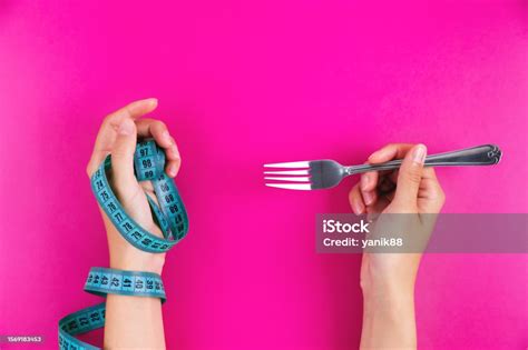 밝은 분홍색 배경에 포크와 줄자를 손에 들고 있다 줄자로 손을 묶고 포크를 들고 있는 여자 클로즈업 가냘픈에 대한 스톡 사진 및 기타 이미지 Istock