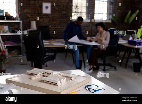 Building Model With Diverse Architects Discussing Blueprints In Background At Office Copy Space