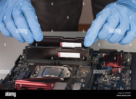Close Up Of Man Hands With Gloves Installing Ram DDR4 Memory Module In Slot On Motherboard Stock