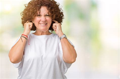 시끄러운 음악의 소음에 대 한 짜증 표현과 손가락으로 귀를 덮고 고립 된 배경 위에 흰색 티셔츠를 입고 아름 다운 중간 거 시 수석 여자 청각 장애 개념 T 셔츠에 대한