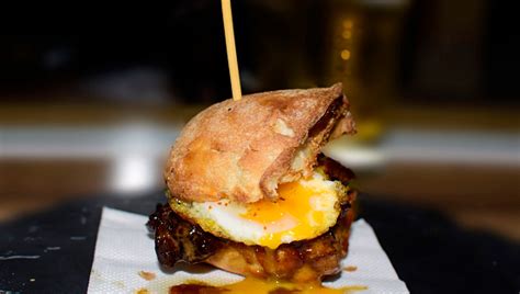 구운 앵거스 쇠고기 베이컨 치즈 메추라기 계란 튀김 크림 소스를 곁들인 미니 버거를 크래프트 페이퍼와 나무 배경에 넣습니다 핀쵸 과자에 대한 스톡 사진 및 기타 이미지