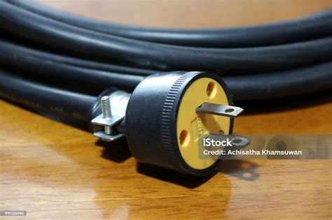 Colokan Kuning Dengan Kabel Hitam Di Lantai Kayu Digunakan Untuk