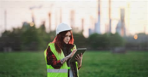 안전모와 태블릿을 쓴 젊은 여성 엔지니어가 정유 공장 옆에 서 있습니다 공간을 복사합니다 사진 Unsplash의 연료 및