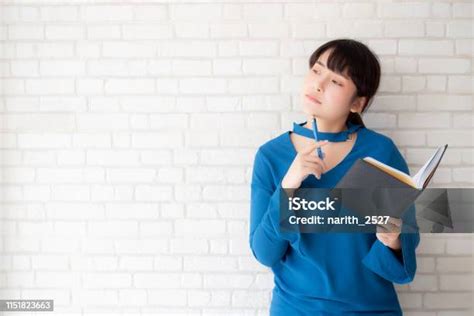 집에서 콘크리트 시멘트 흰색 배경에 노트북을 생각 하 고 쓰기 서 서 웃는 아름 다운 아시아 여자 책 교육 및 라이프 스타일