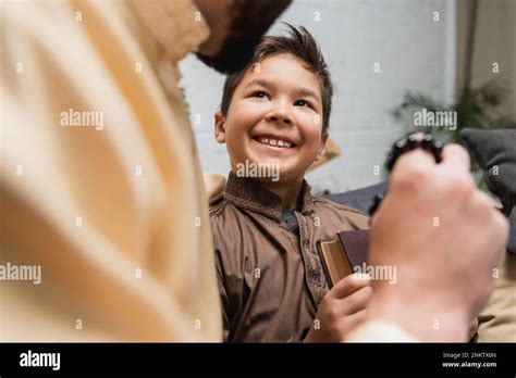 Blurred Muslim Dad With Prayer Beads Near Smiling Son Holding Book At Home Stock Image Stock
