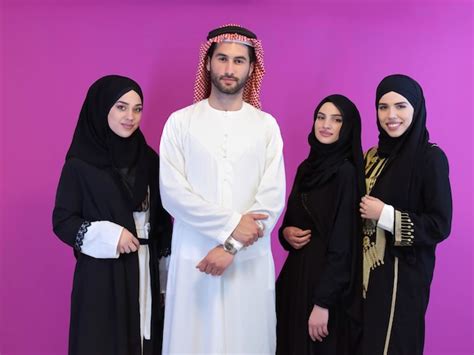 伝統的な服を着たイスラム教徒の若者のポートレート。幸せなアラビア語の家族が一緒に、男とピンクの背景に分離された 3 人の女性 Premium写真