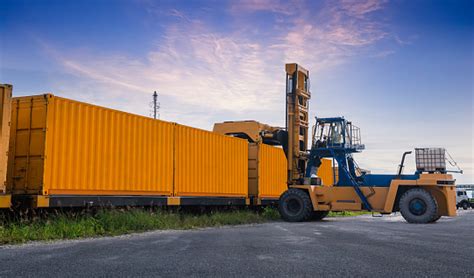 지게차 트럭은 기차역에서화물 컨테이너를 들어 올리고 있으며 유통 터미널 물품을 기다리는 철도는 수입 및 수출 물류 운송 사업 개념입니다 0명에 대한 스톡 사진 및 기타