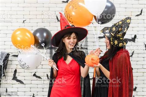 두 아름다운 젊은 아시아 여자 마녀 할로윈 의상 에 호박 잭 O 랜턴과 풍선 에 흰색 벽돌 배경 에 할로윈 파티를 위한 검은 종이 박쥐 모양으로 장식 2명에 대한 스톡 사진
