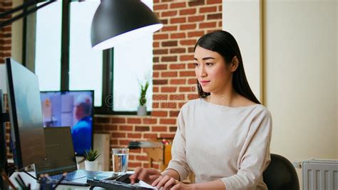 it specialist types code on dual monitors in a cozy home office stock
