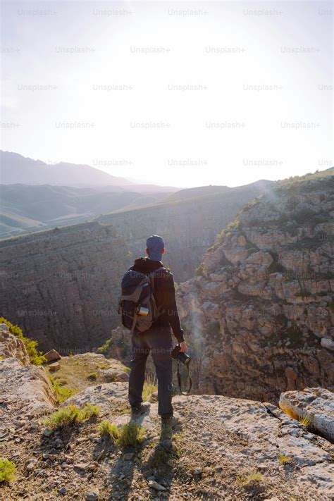 배낭을 메고 있는 남자가 절벽에 서 있다 사진 Unsplash의 이란 이미지