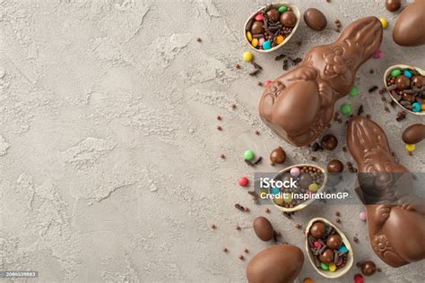 호화로운 현대 부활절 간식이 전시되어 있습니다 깨진 초콜릿 달걀에 생동감 넘치는 과자 밀크 초콜릿 토끼 매끈한 슬레이트 배경에 뿌려진 것을 보여주는 오버헤드 샷 복사를 위한
