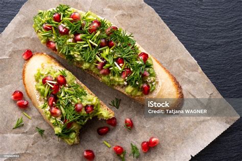 검은 배경의 중간에 양피지 종이에 한 물린 아보카도 석류 씨앗과 딜의 한 가지 전체 간식이 있습니다 클로즈업 건강한 생활방식에 대한 스톡 사진 및 기타 이미지 Istock