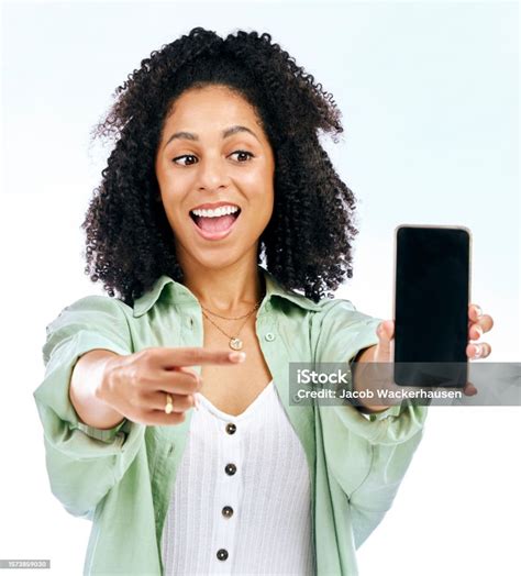 화면 모형 또는 소셜 미디어 또는 제품 배치의 흰색 배경에 전화로 흥분한 여성 포인팅 미소 또는 행복한 사람이 모바일 앱 프로모션 웹사이트 또는 기술 모형 스튜디오에서