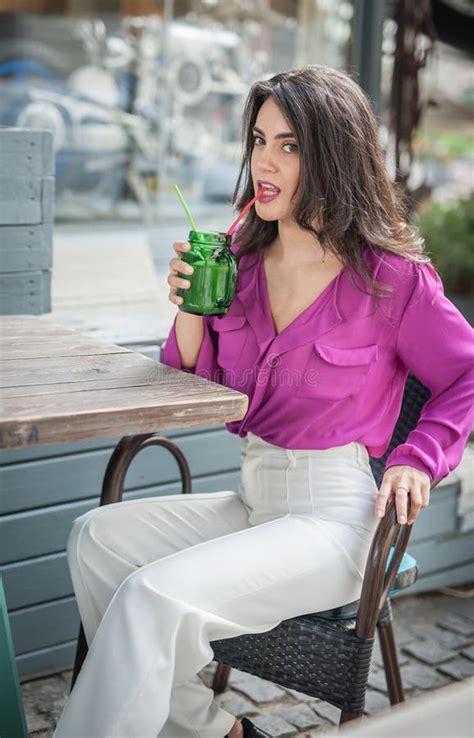 Happy Brunette Girl With Pink Blouse Sitting At The Bar Drinking A