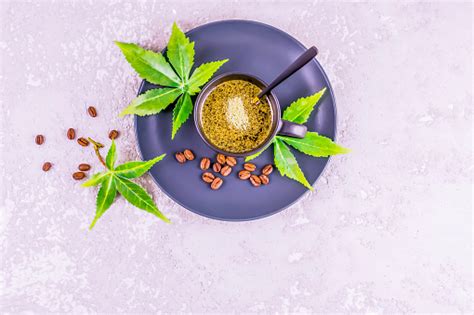 접시에 향기로운 커피와 콩나비스 잎이 있는 다크 컵은 회색 콘크리트 배경에 서 있습니다 에너지에 대한 모닝 커피의 개념 가루로