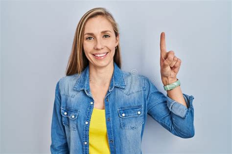 Young Blonde Woman Standing Over Blue Background Showing And Pointing